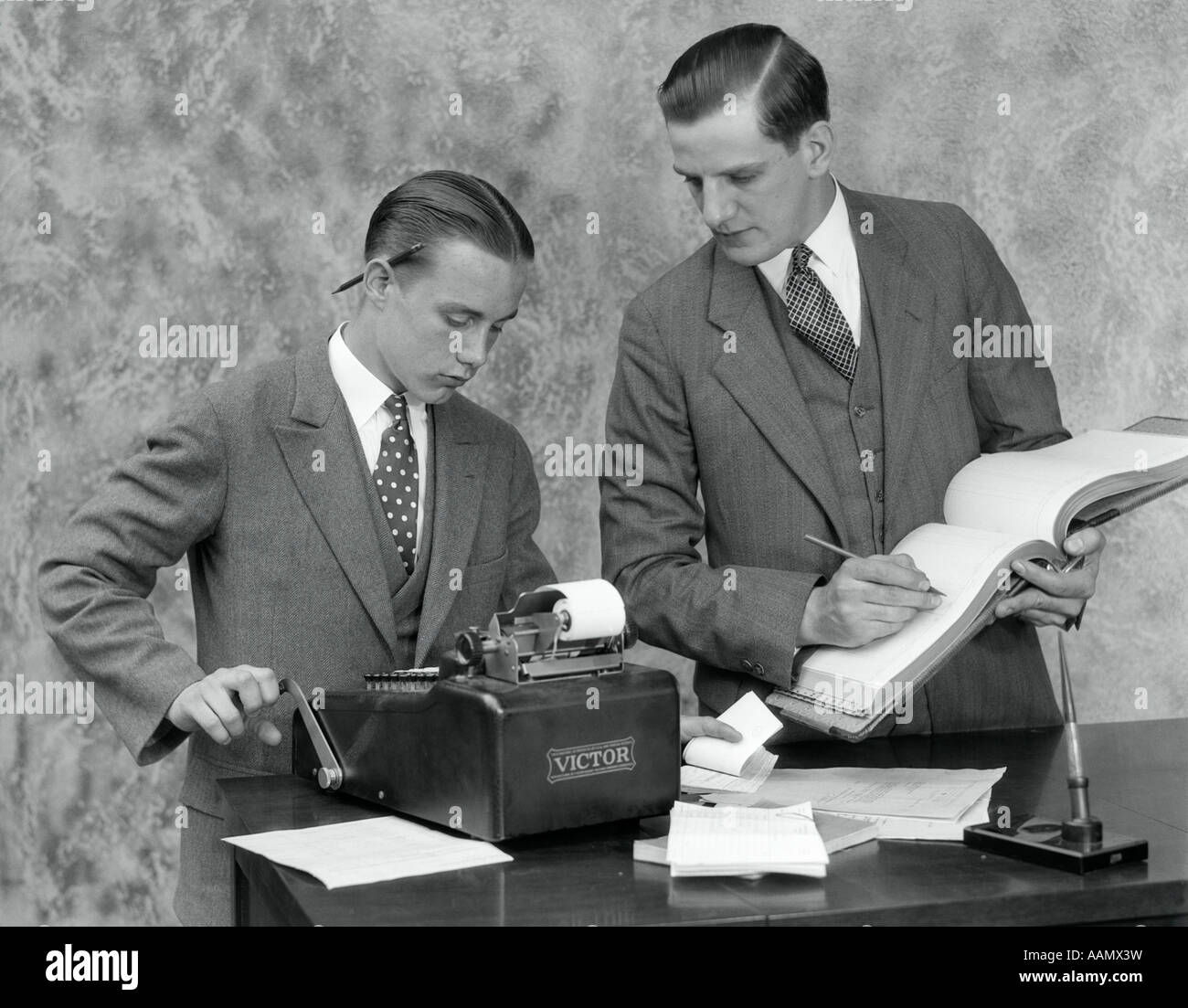 1930s CLERK AND YOUNG ASSISTANT IN OFFICE USING LEDGER BOOK & ADDING ...