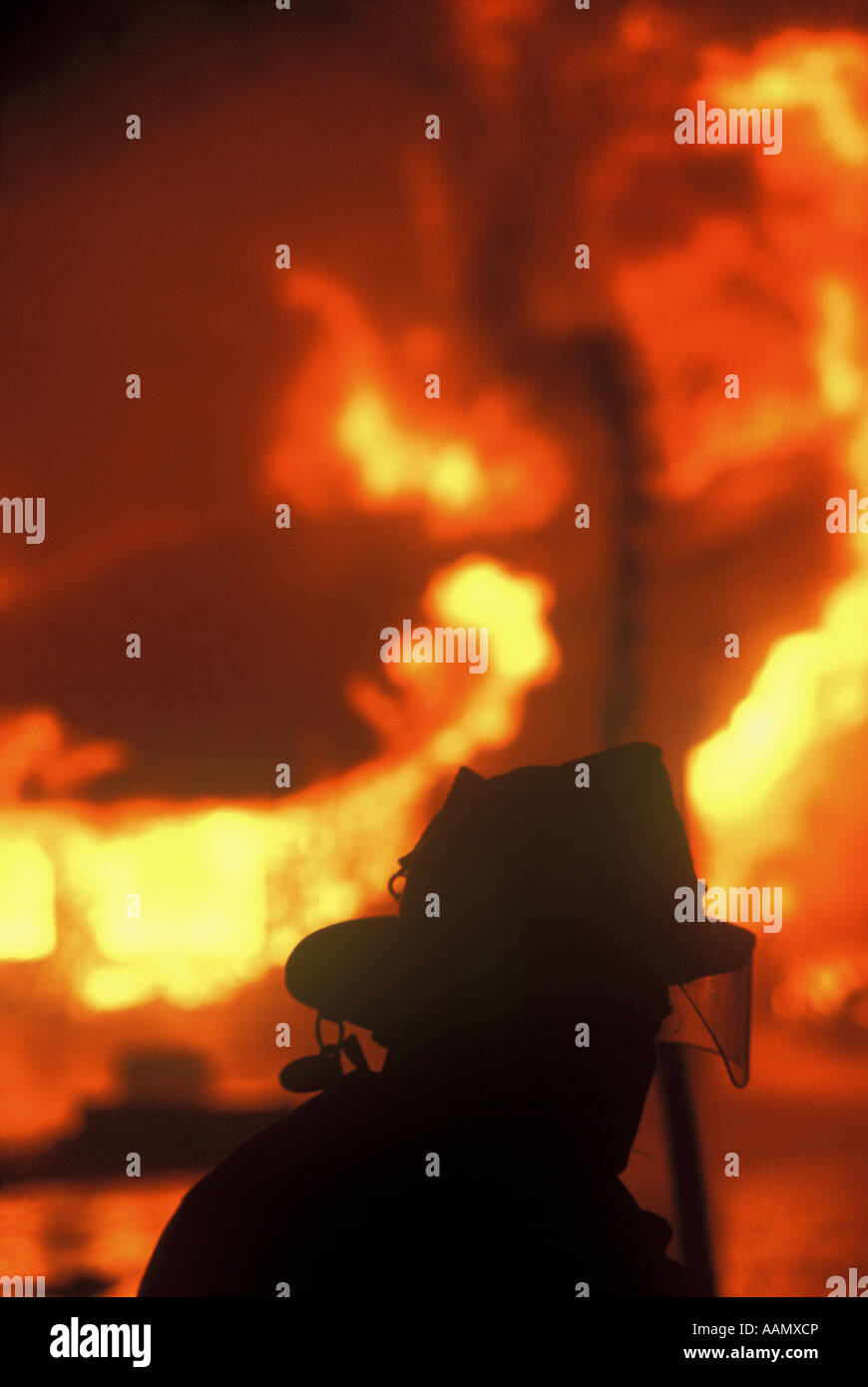 Fire fighter silhouetted with hose putting out a house fire Stock Photo ...