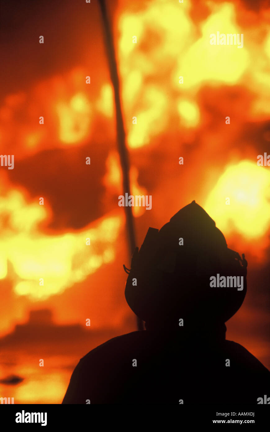 Fire fighter silhouetted with hose putting out a house fire Stock Photo ...