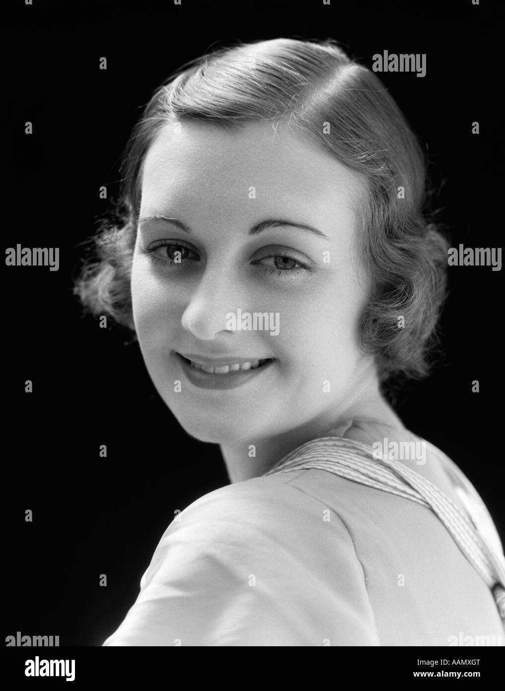 1930s SMILING YOUNG WOMAN HEAD TURNED OVER HER SHOULDER LOOKING AT ...