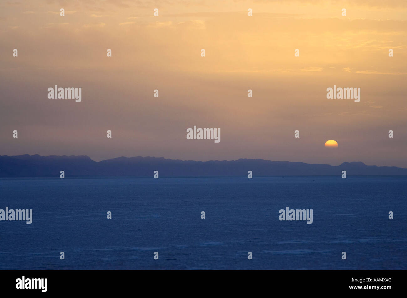 The sun breaking through clouds over the distant mountains and great ...