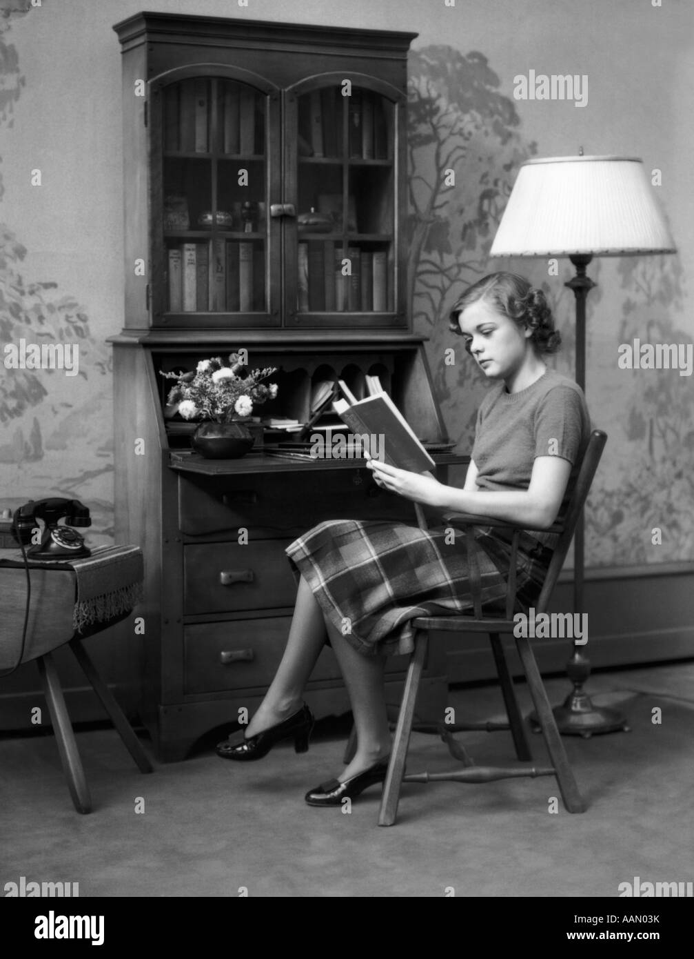 1930s 1940s YOUNG WOMAN TEENAGE SITTING IN A CHAIR READING A BOOK BY A ...