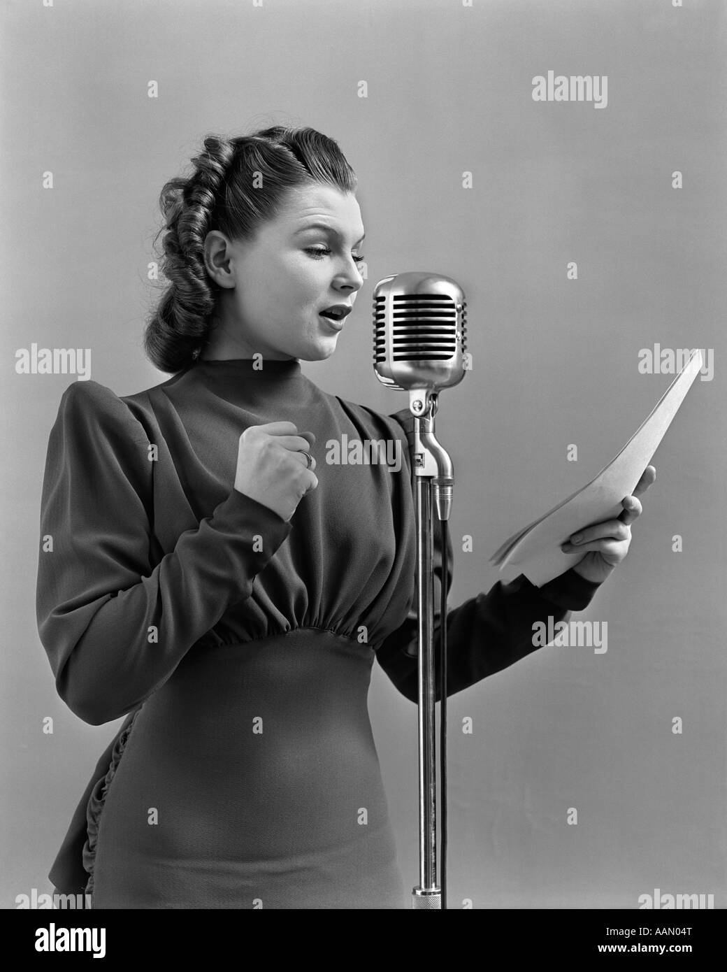 1940s YOUNG WOMAN SPEAKING INTO MICROPHONE READING FROM PAPER DOCUMENT ...