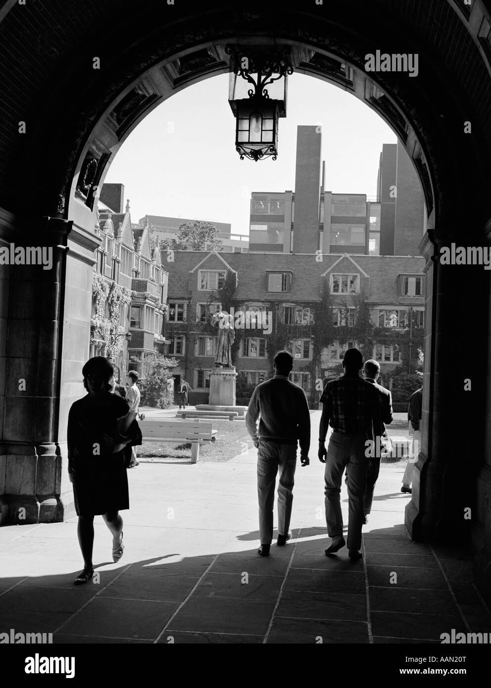 1960s COLLEGE STUDENTS WALKING THROUGH ARCHWAY IN CAMPUS BUILDING WITH ...