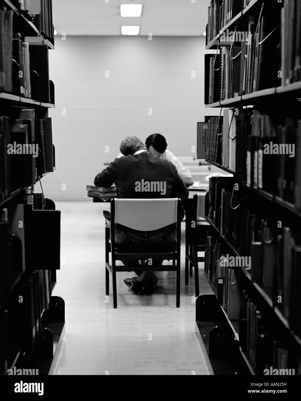 1970s PAIR OF MALE COLLEGE STUDENTS STUDYING IN LIBRARY FRAMED BY ...