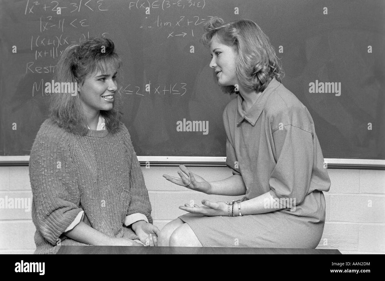 TWO STUDENTS IN COLLEGE CLASSROOM WOMAN TALKING TO EACH OTHER ...