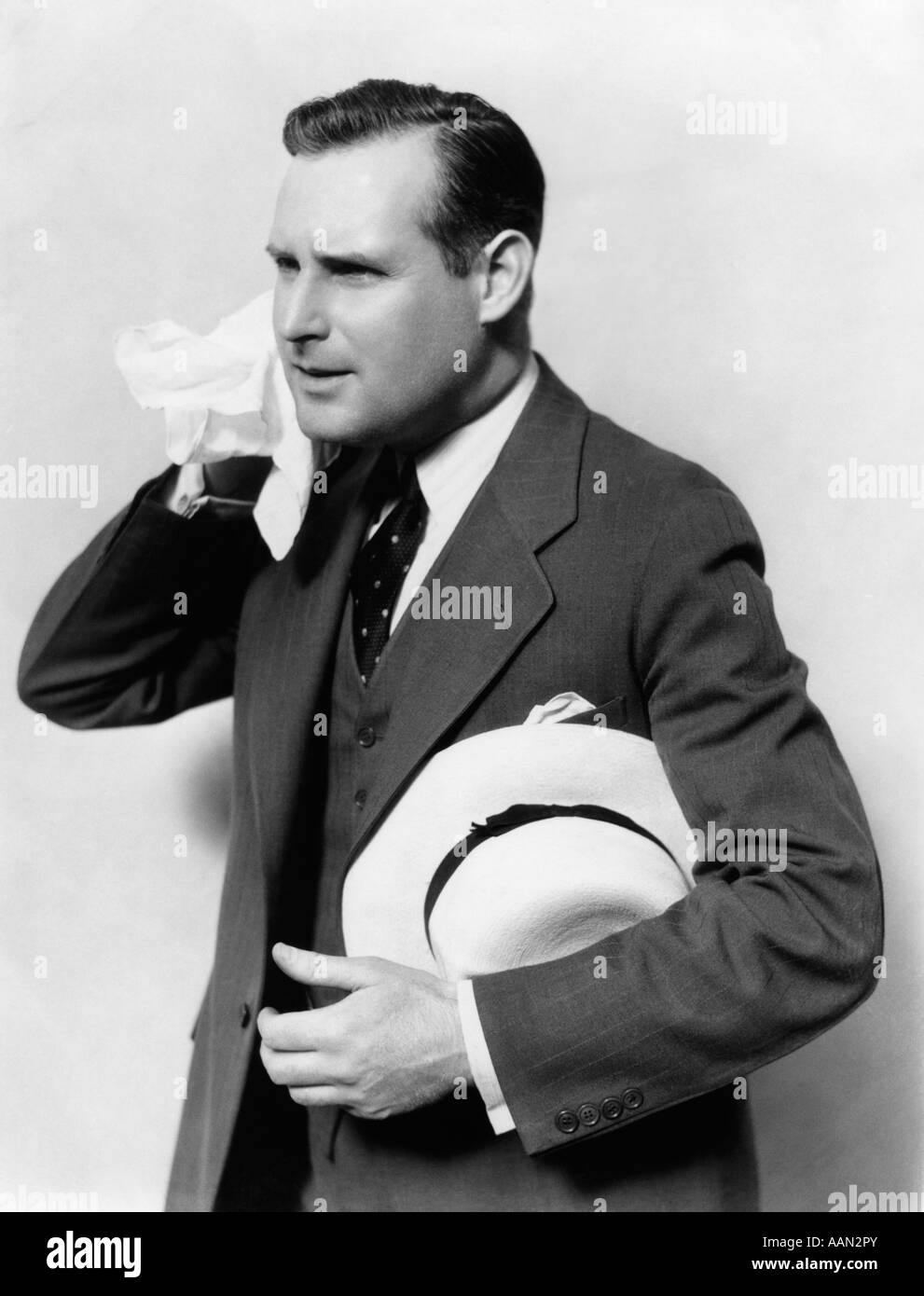 1930s MAN IN SUIT HOLDING HAT WIPING FACE WITH HANDKERCHIEF Stock Photo ...
