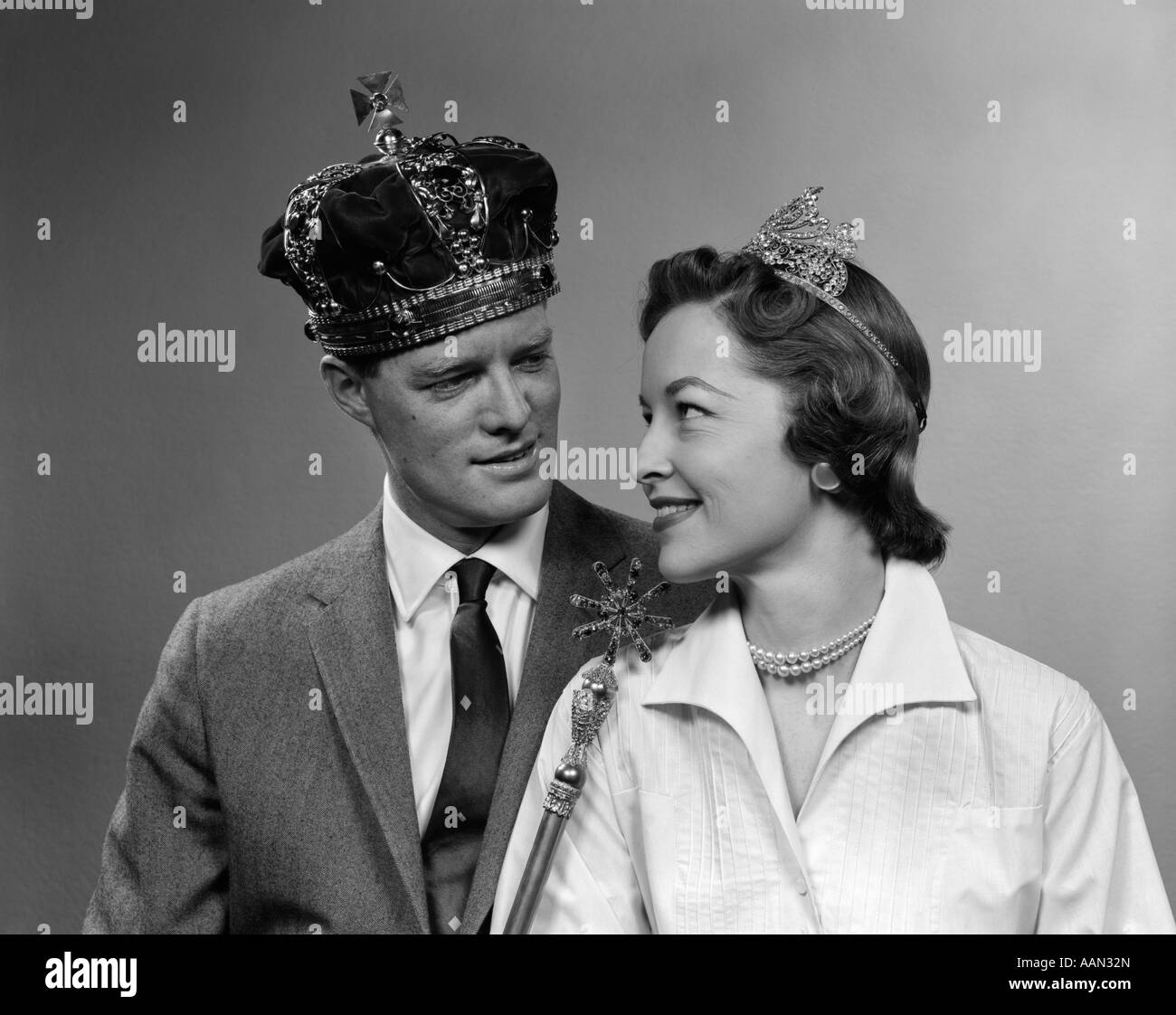 1950s MAN & WOMAN WEARING KING & QUEEN CROWNS LOOKING AT EACH OTHER MAN ...