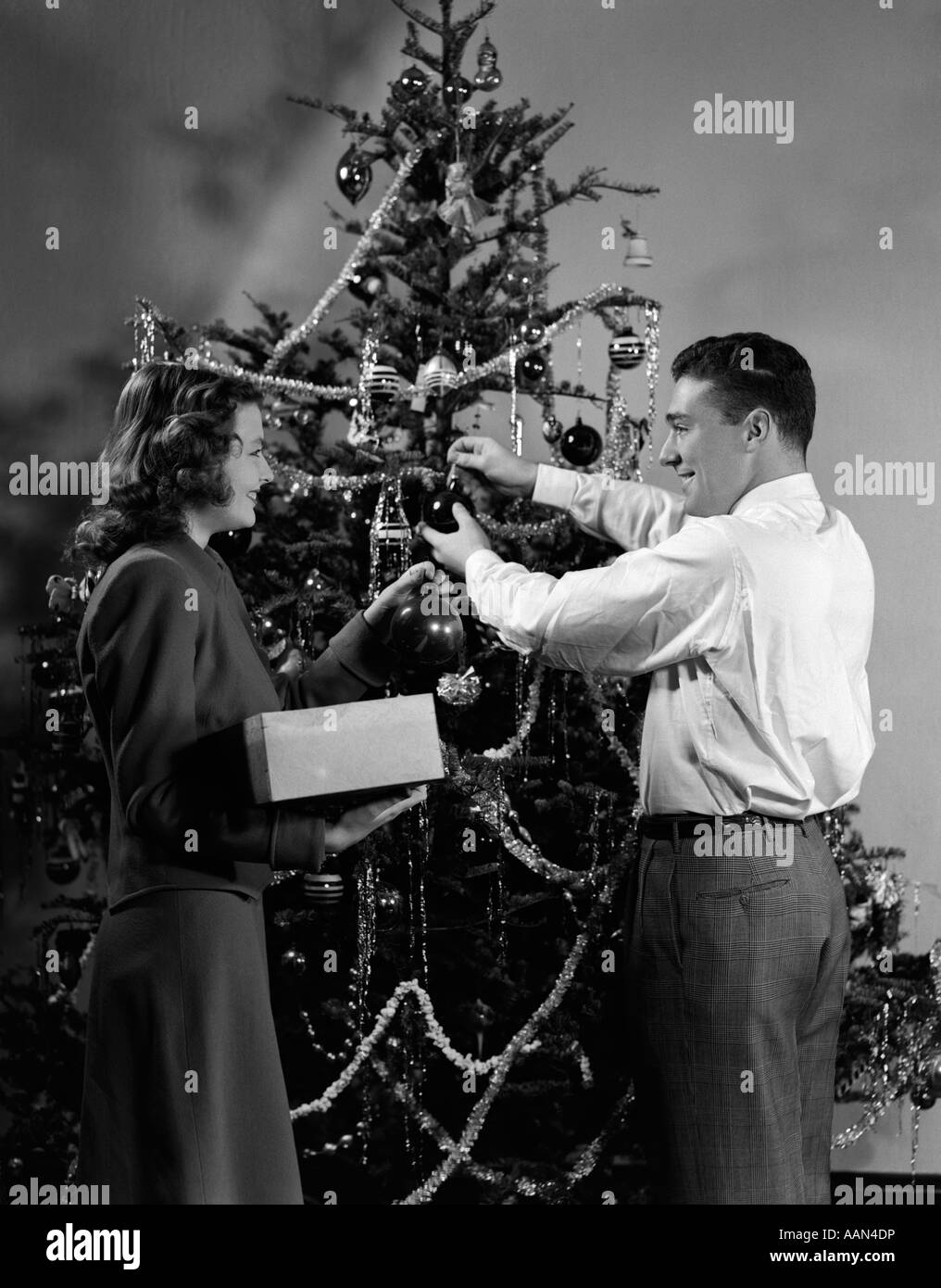 1940s COUPLE DECORATING CHRISTMAS TREE WITH ORNAMENTS Stock Photo - Alamy
