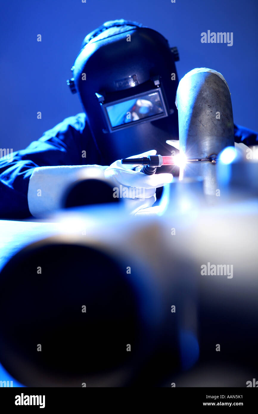 Welder welding stainless steel pipework on a work bench Stock Photo - Alamy