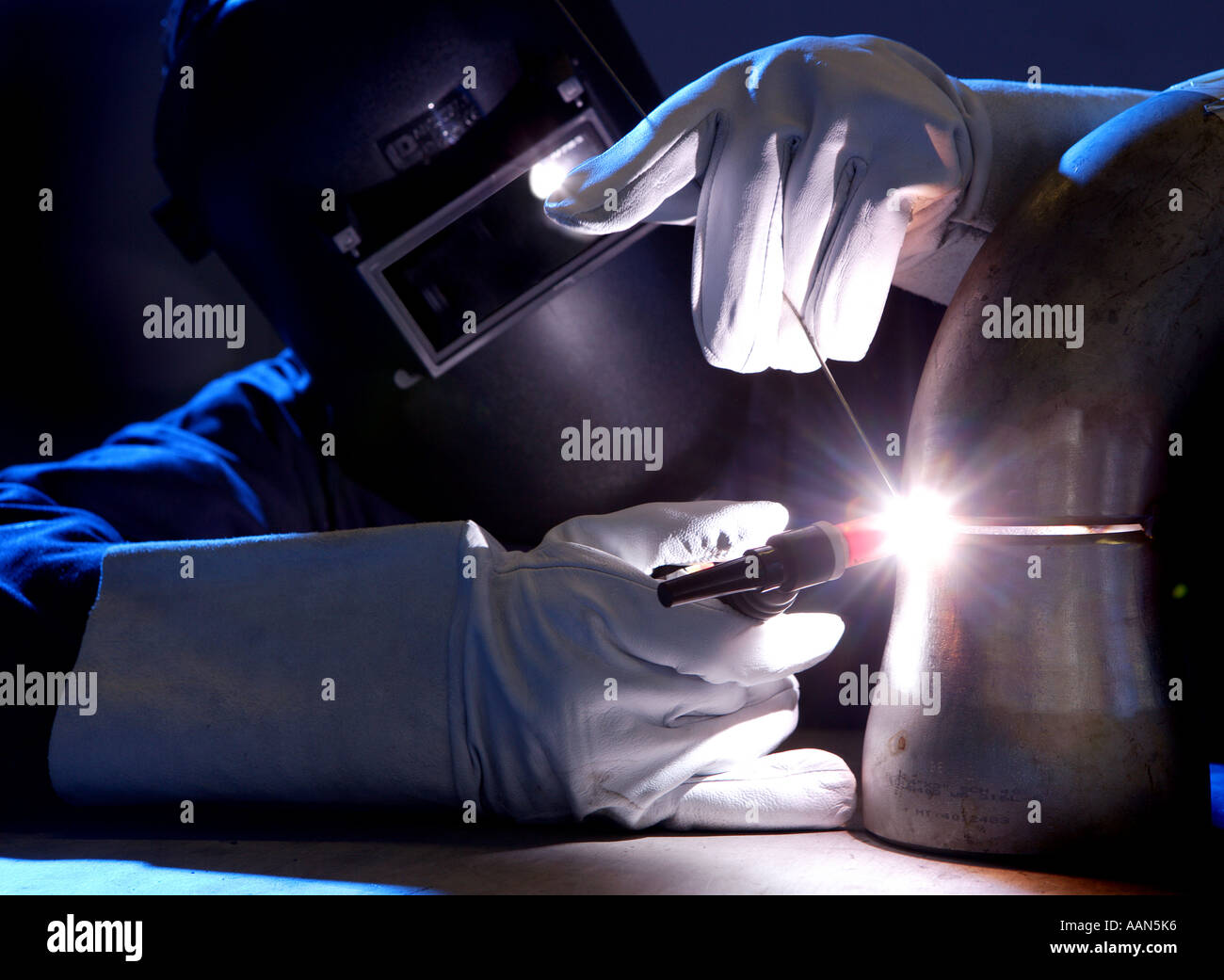 Welder welding stainless steel pipework on a work bench Stock Photo - Alamy