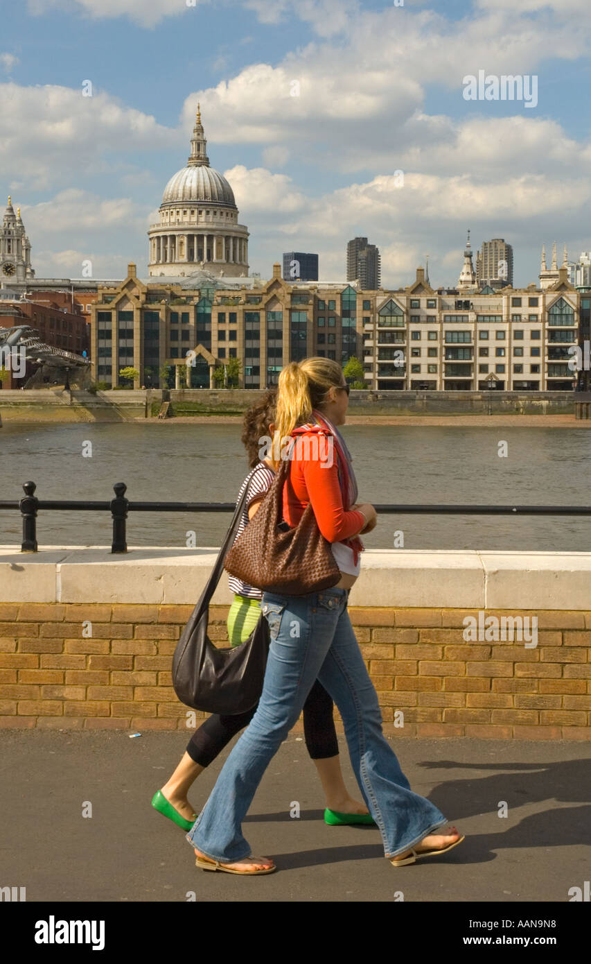 Two women walking along the Thames in central London England UK Stock ...