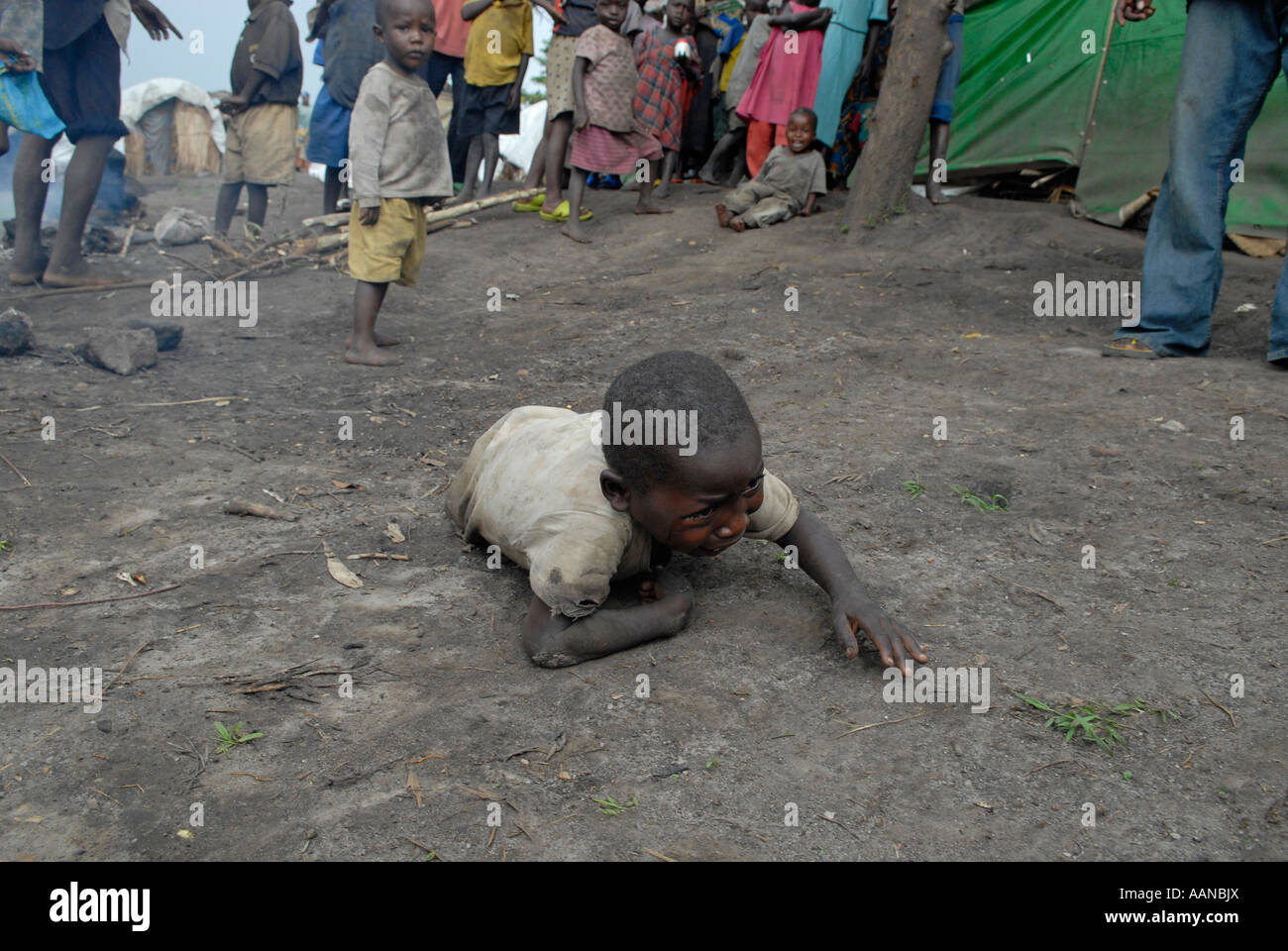 Young boy crawling on the ground and crying in an a camp for internal ...