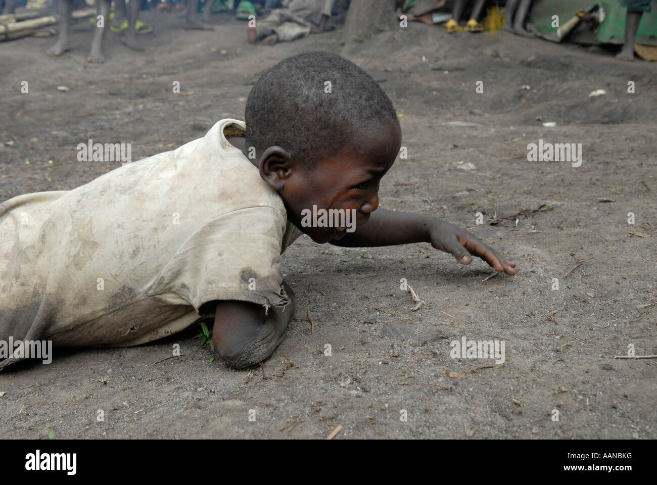 Young boy crawling on the ground and crying in an a camp for internal ...