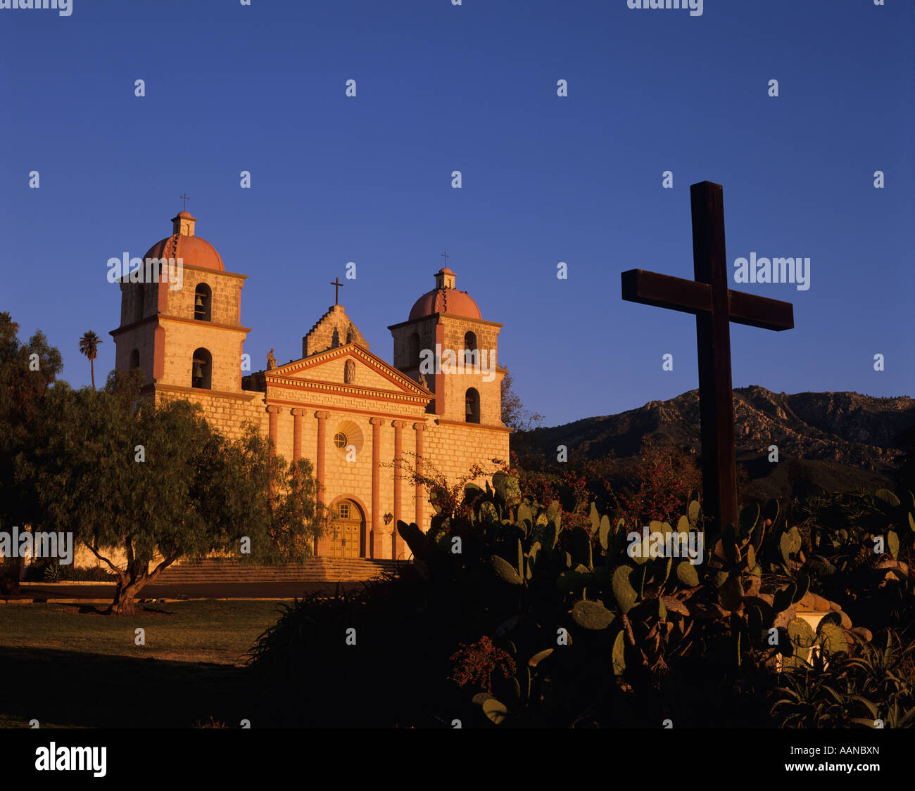 Santa Barbara Mission at sunrise with warm light on facade and cross ...