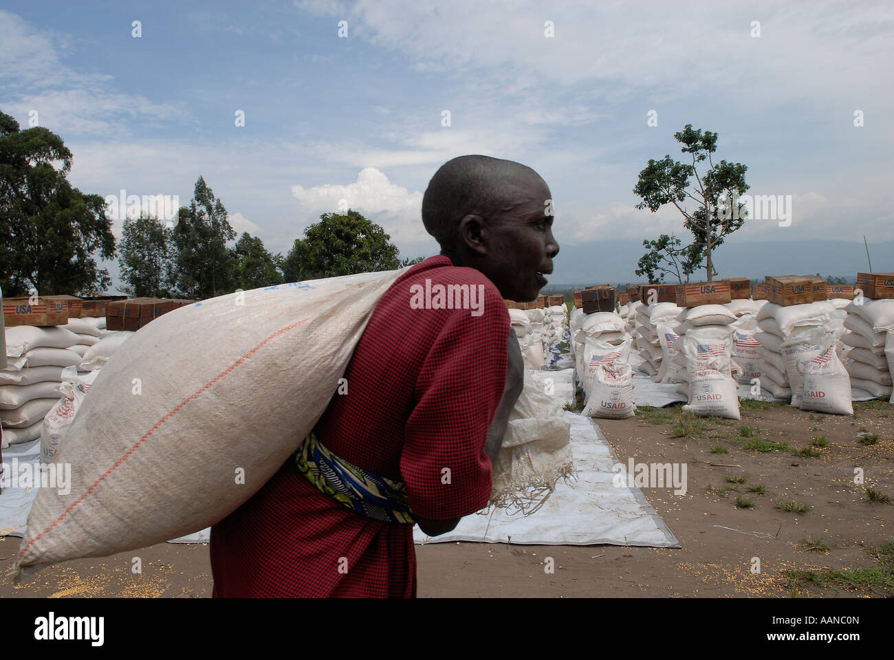 Internally displaced woman carries large sack of corn soya blend at ...