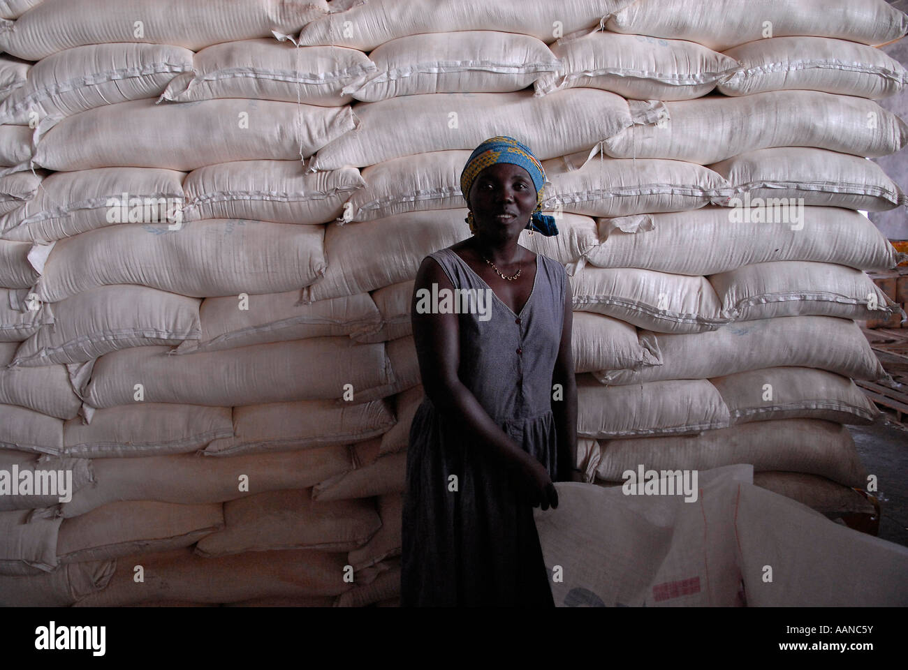 A woman stands amid sacks of basic foodstuffs at a storage warehouse of ...