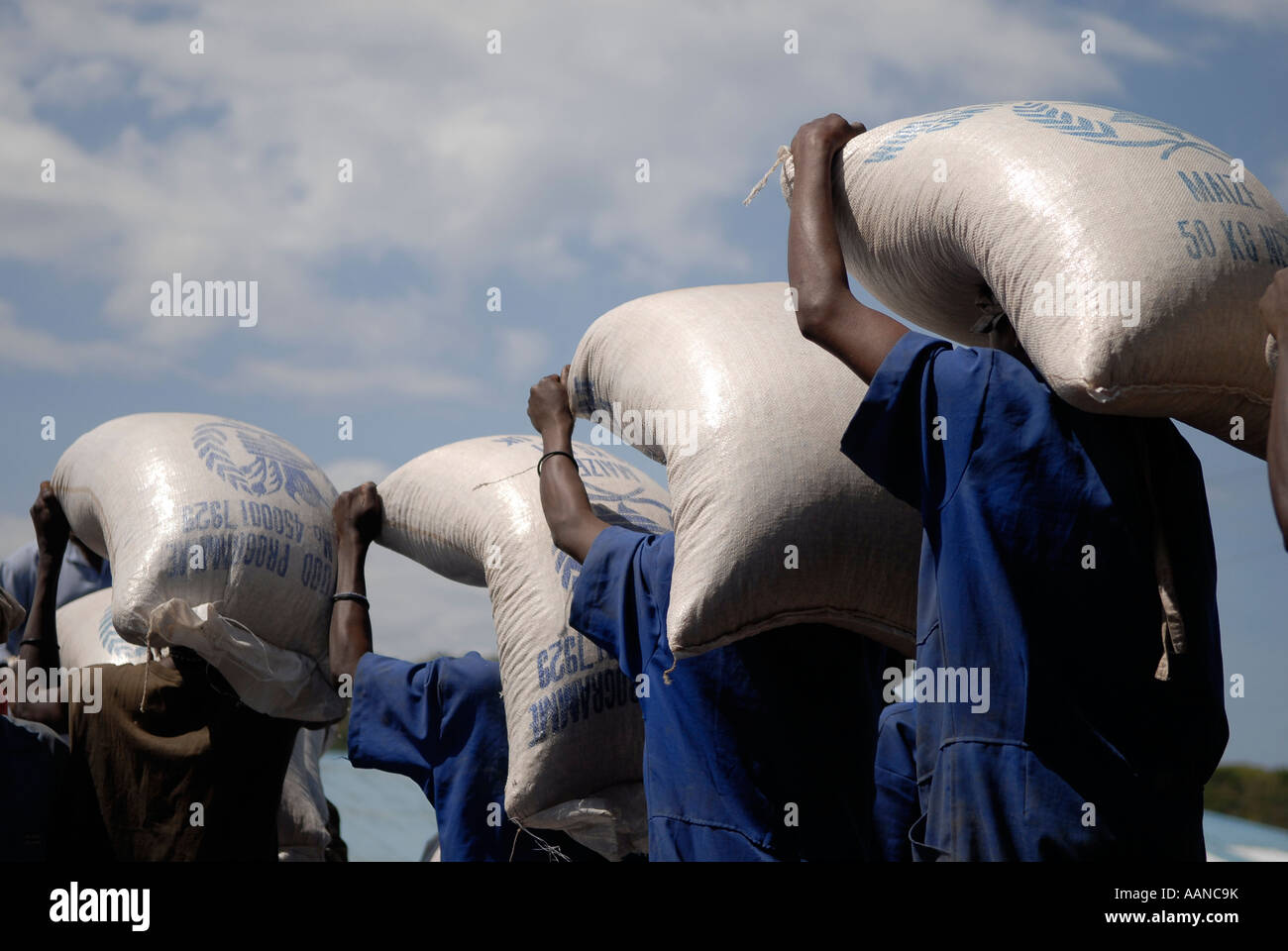 Men carrying large sacks of corn soya blend at a World Food Programme ...