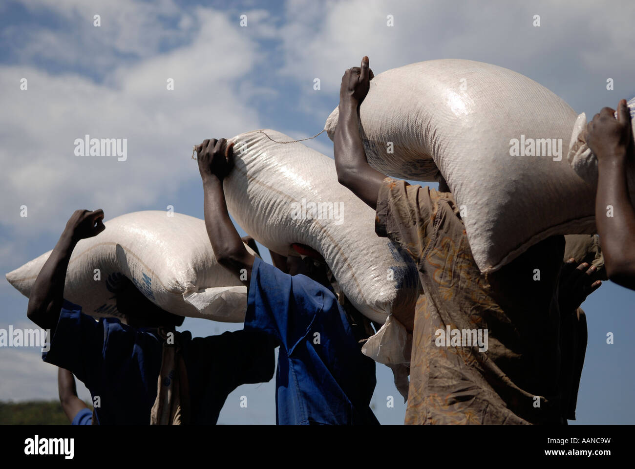 Men carrying large sacks of corn soya blend at a World Food Programme ...