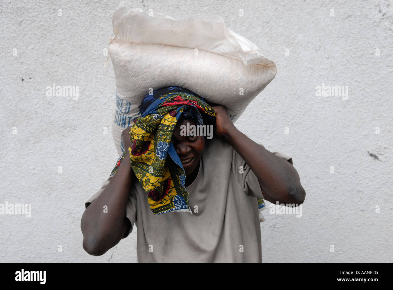 An Internally displaced woman carries large sack of corn soya blend ...