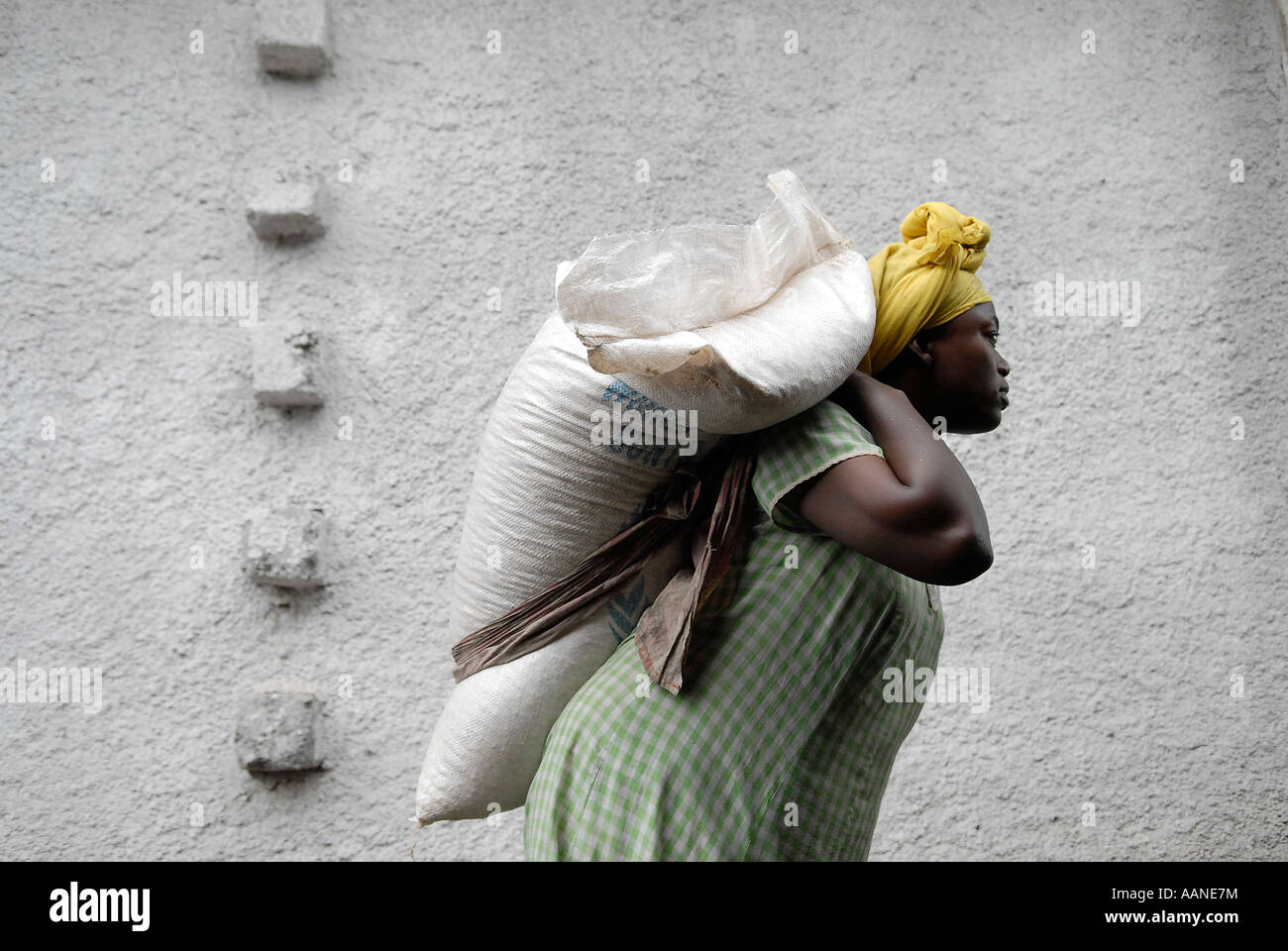 Internally displaced woman carries large sack of corn soya blend at ...