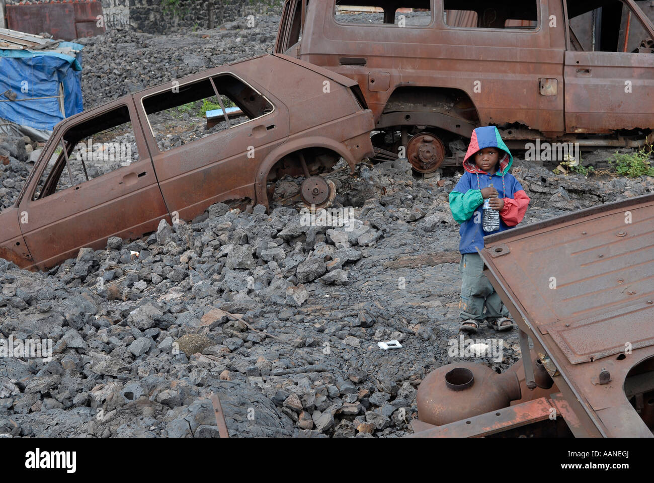 A boy stands amid vehicles embedded in dry volcano lava due to 2002 ...
