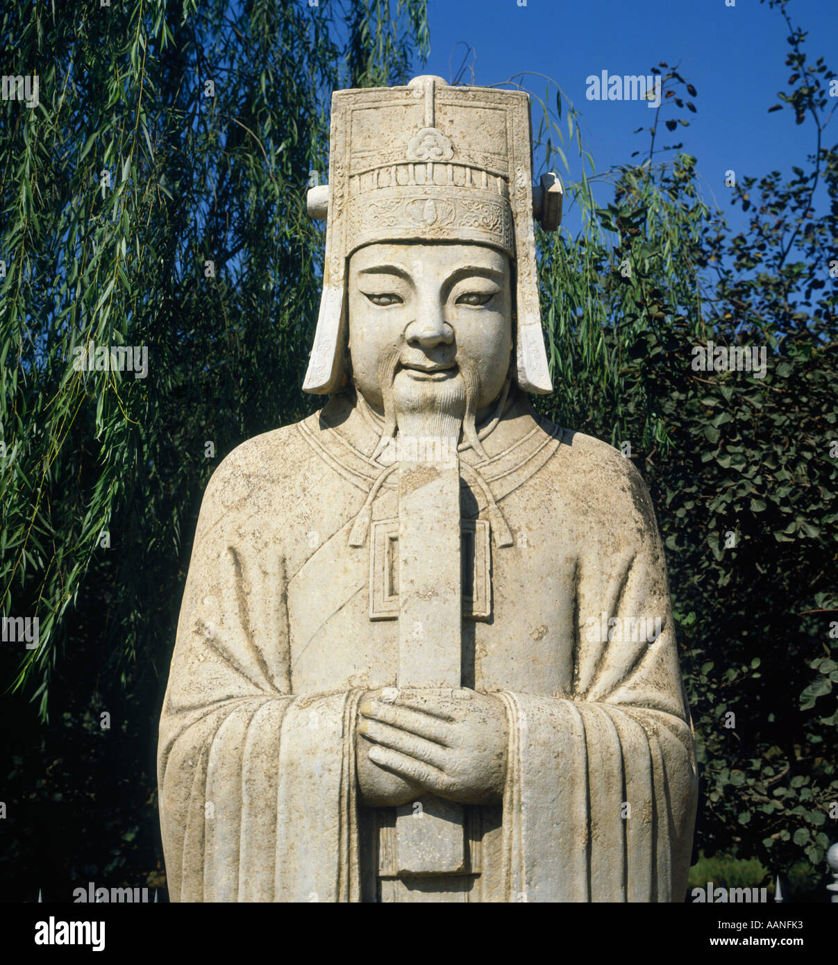 Stone statue in robes and headdress at the roadside to the Sacred Way ...