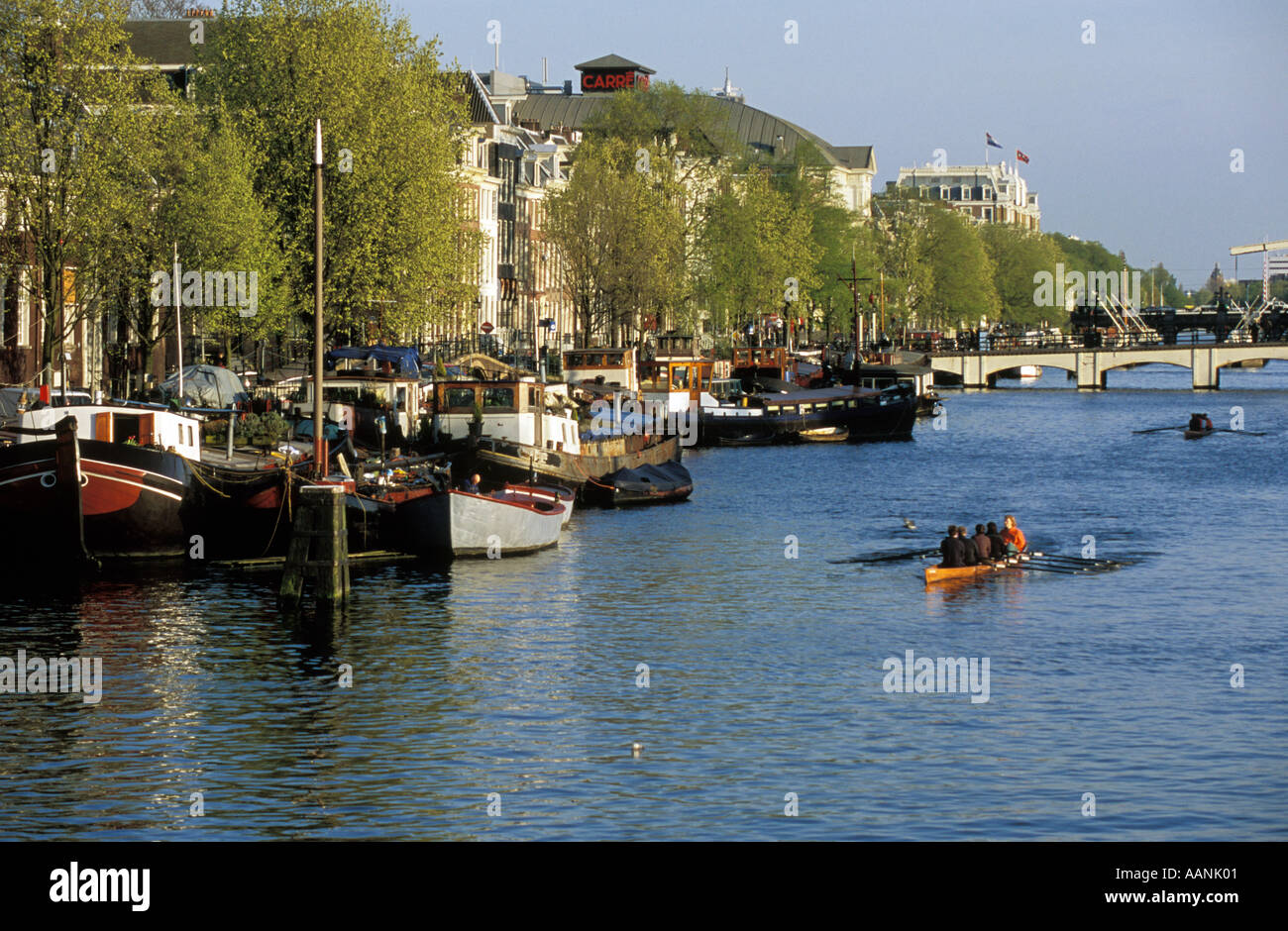 Amsterdam, Holland Rowers in shell boat paddling up the canal Boats ...