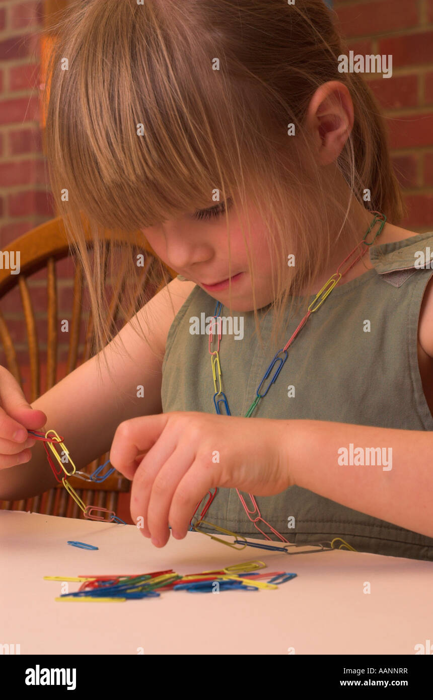 Young child 4 5 making a chain out of paper clips Stock Photo - Alamy