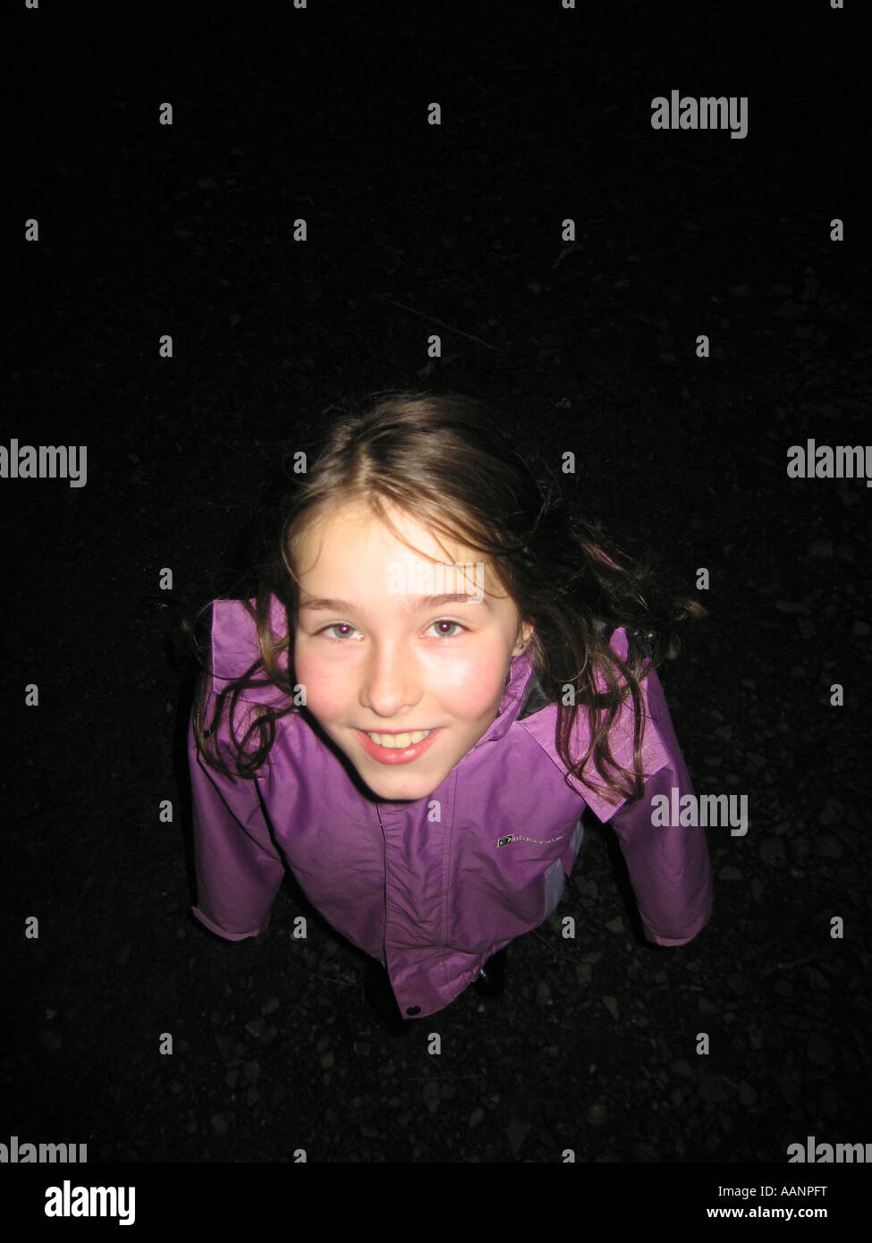 Young girl smiling up at camera with cheeky expression Stock Photo - Alamy