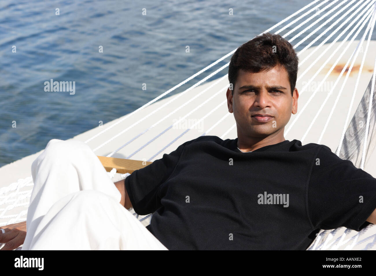 Indian Man relaxing in Hammock By Ocean Stock Photo - Alamy