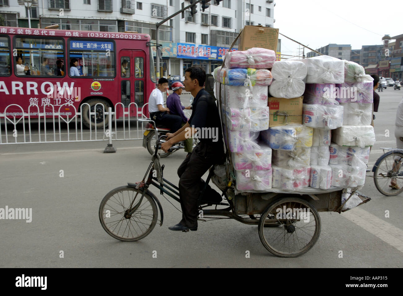 Man carrying a heavy load on his tricycle as he travels through city ...