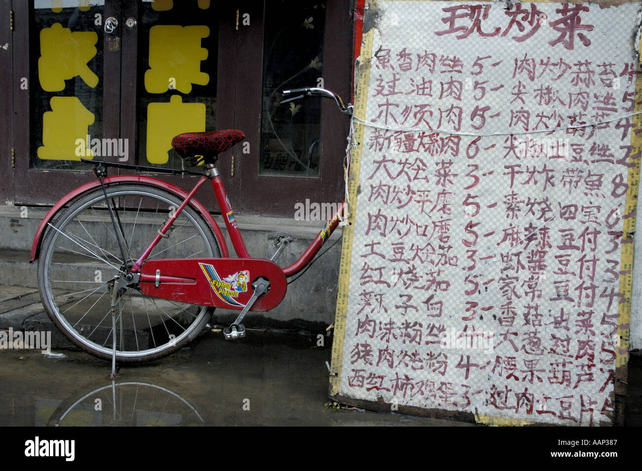 Red bicycle parked behind a long list of menu prices by a restaurant in ...
