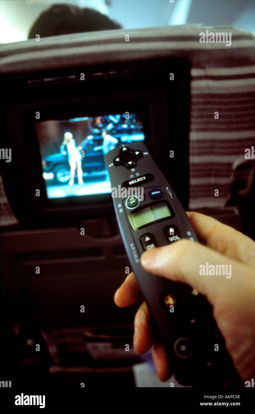 Passenger using remote control for in flight entertainment on seat back ...