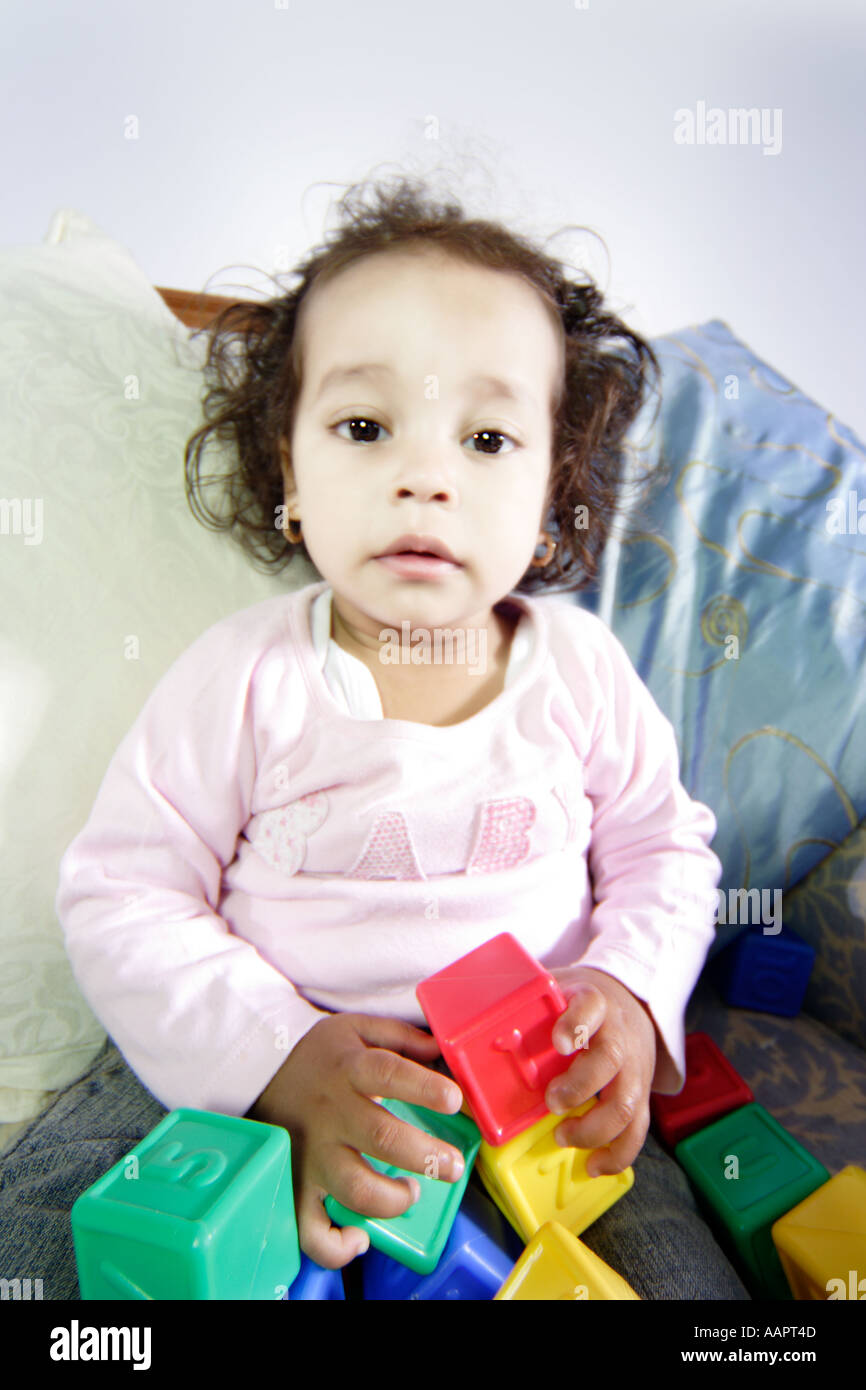 Young baby toddler aged sat on a chair with learning blocks looking ...