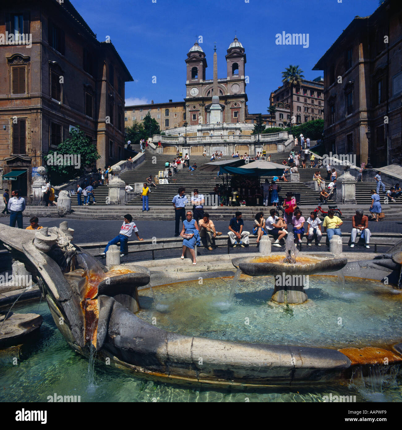 Spanish Steps people sitting around Barcaccia Fountain with steps ...