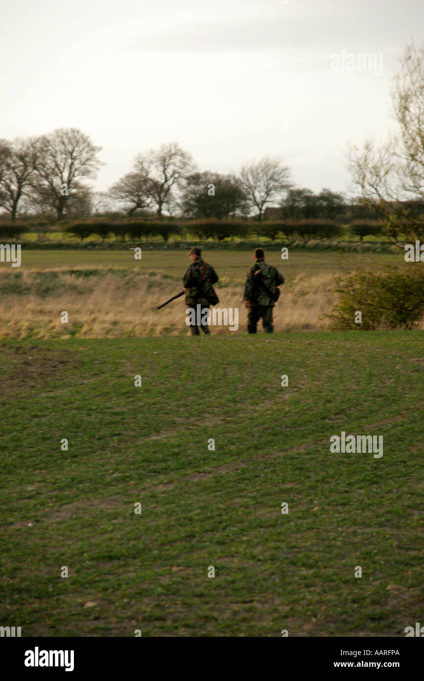 Two men wearing clothing of disruptive pattern material with shotguns ...