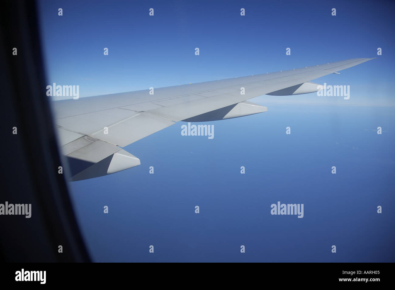 Wing and porthole inside a flying airplane Stock Photo - Alamy