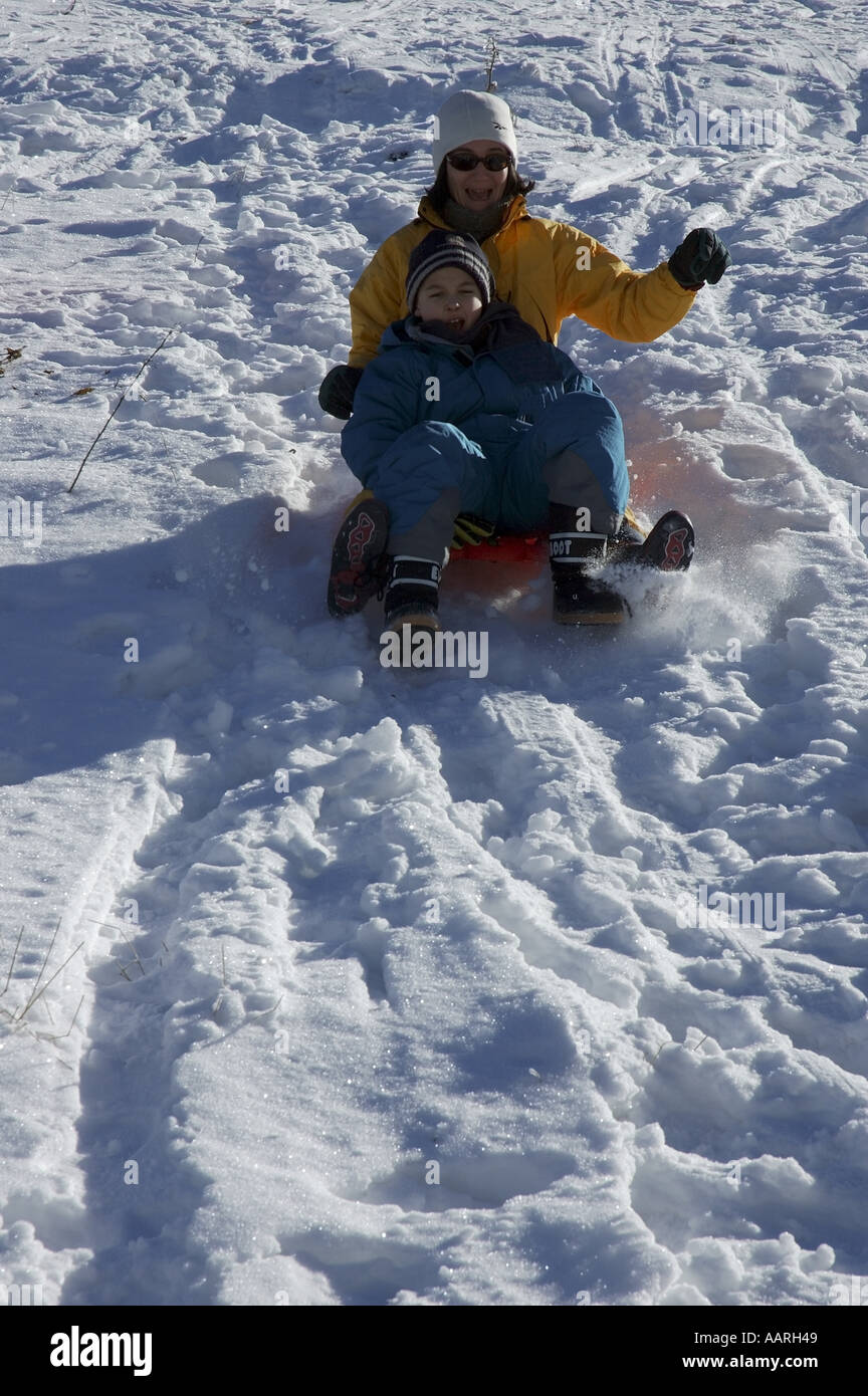 A Children And His Mother Sledding On The Same Sled Together Stock ...