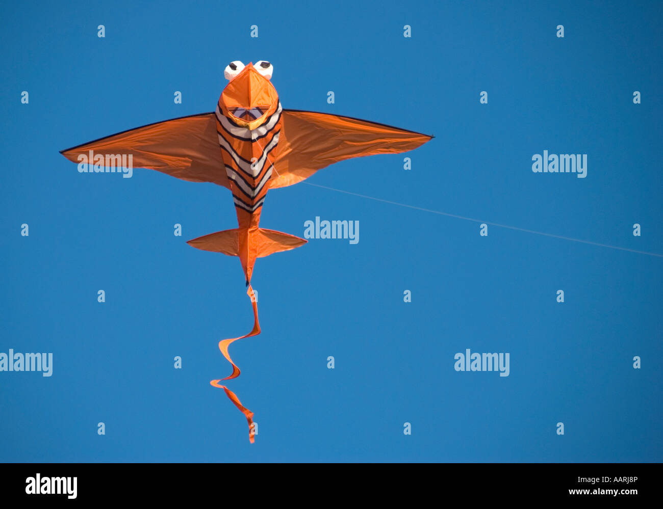 Orange Fish shape kite flying against clear blue sky Stock Photo - Alamy