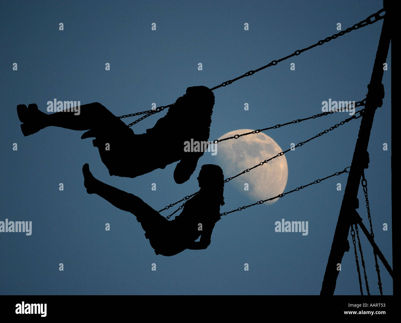 Composite picture of silhouette of two girls on swings against a dark sky with moon Stock Photo ...