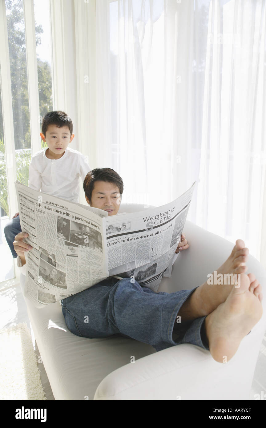 Father reading newspaper in sofa Stock Photo - Alamy