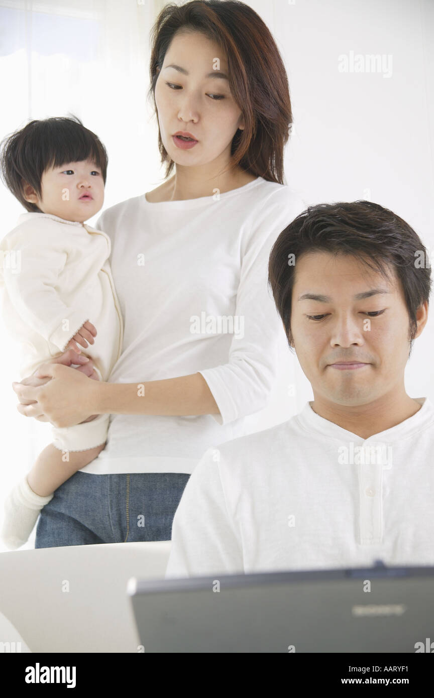 Father using computer with mother standing behind Stock Photo - Alamy