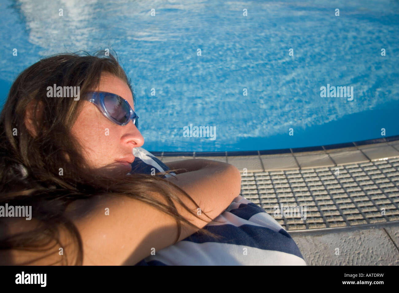 Young woman sleeping by pool in sunshine Stock Photo - Alamy