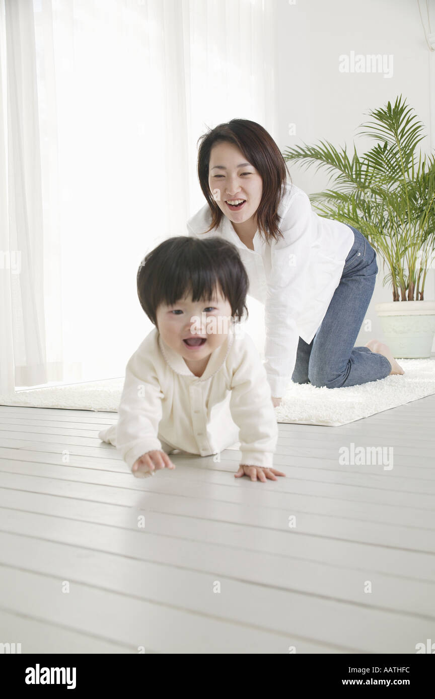 Baby girl crawling and mother following Stock Photo - Alamy