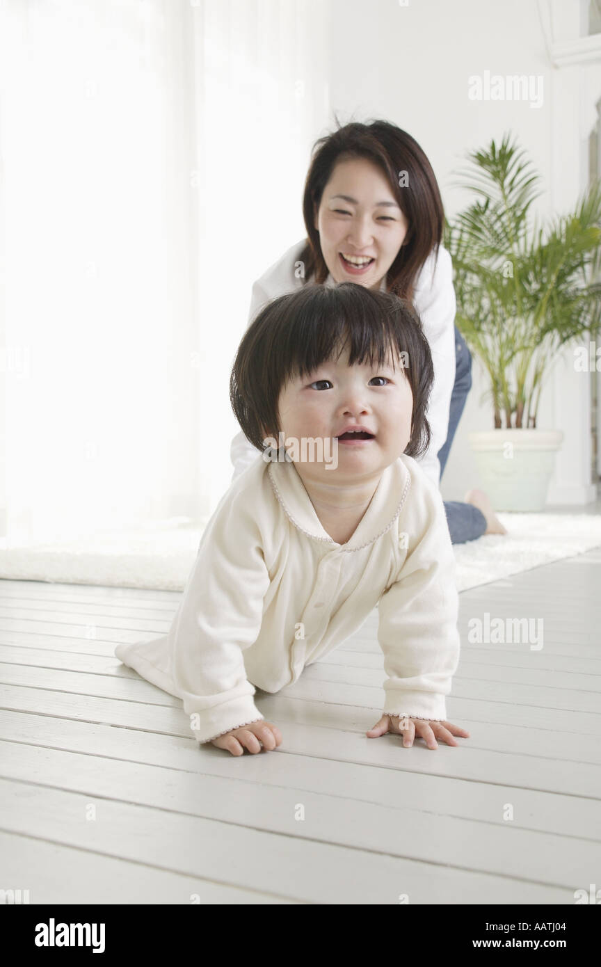 Baby girl crawling and mother following Stock Photo - Alamy