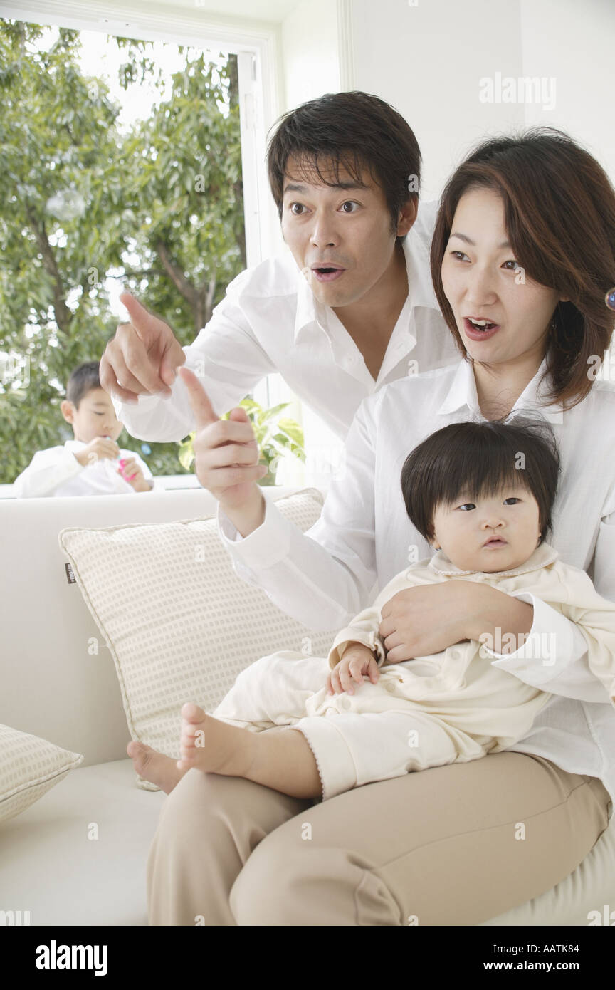 Parents pointing at something with baby girl sitting on mother's lap ...