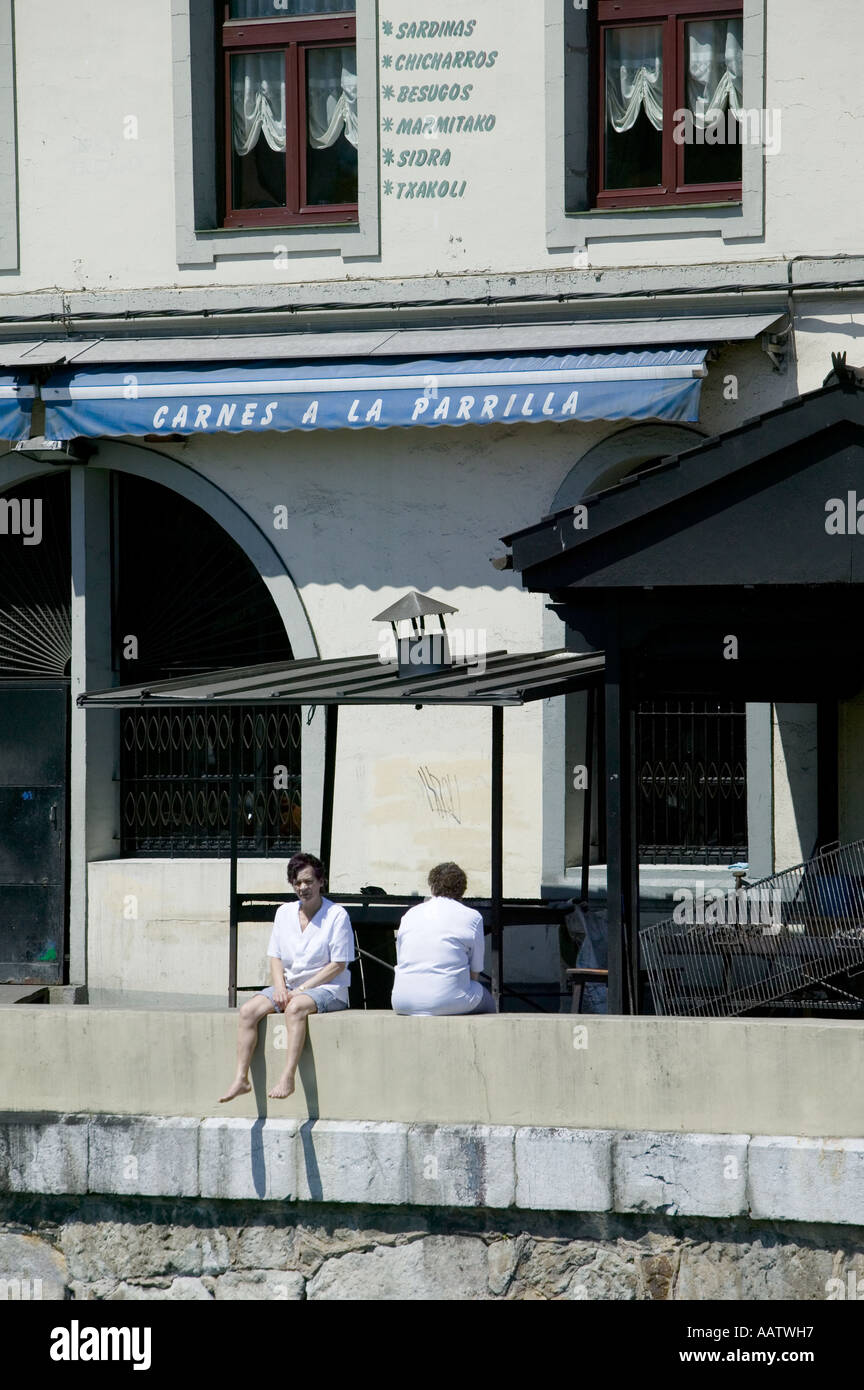 Two waitresses sitting in sun outside restaurant, Fishermans Dock ...