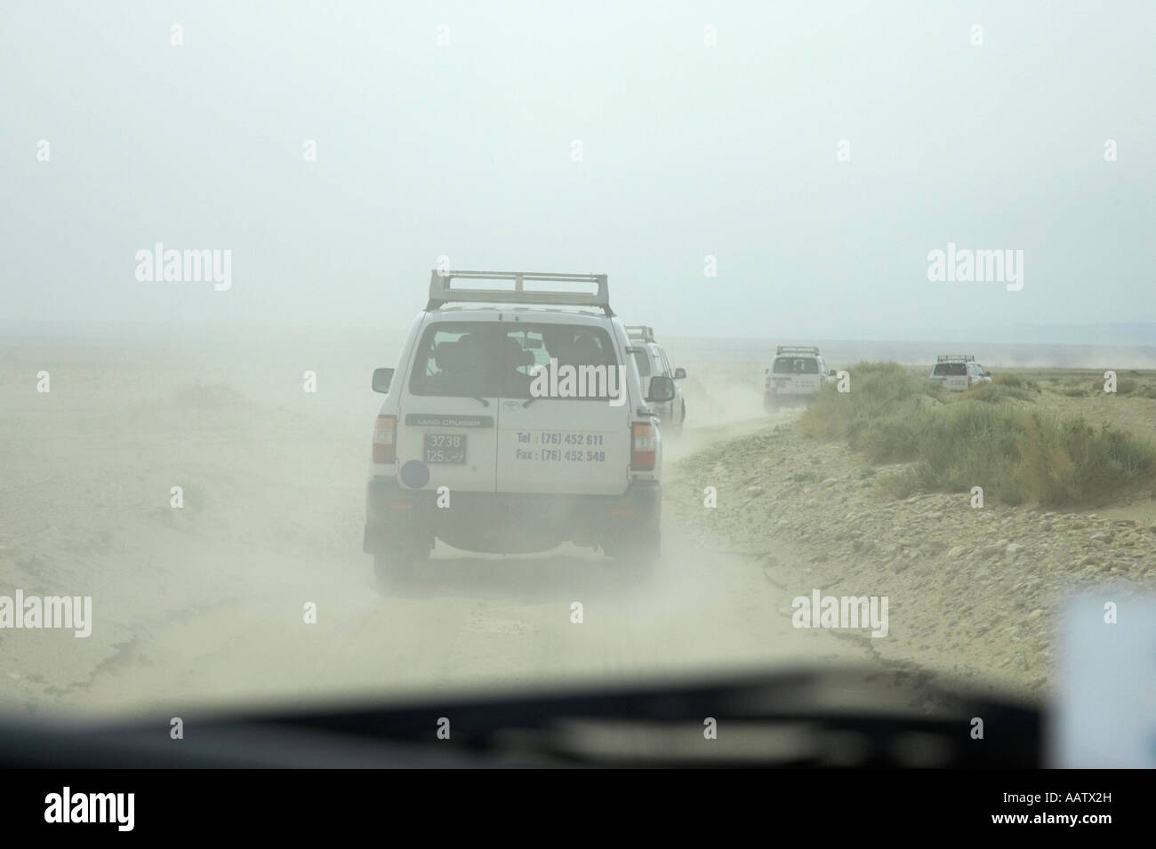 in a convoy of off road vehicles driving through dusty desert in ... in a convoy of off road vehicles driving through dusty desert in ...