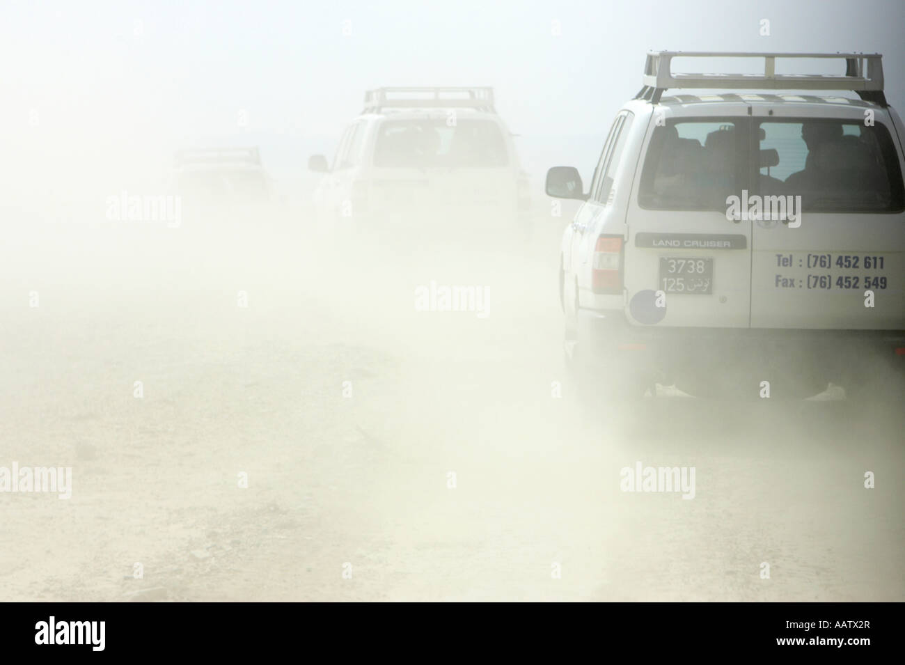 off road vehicles disappearing in a large cloud of dust in the desert ...